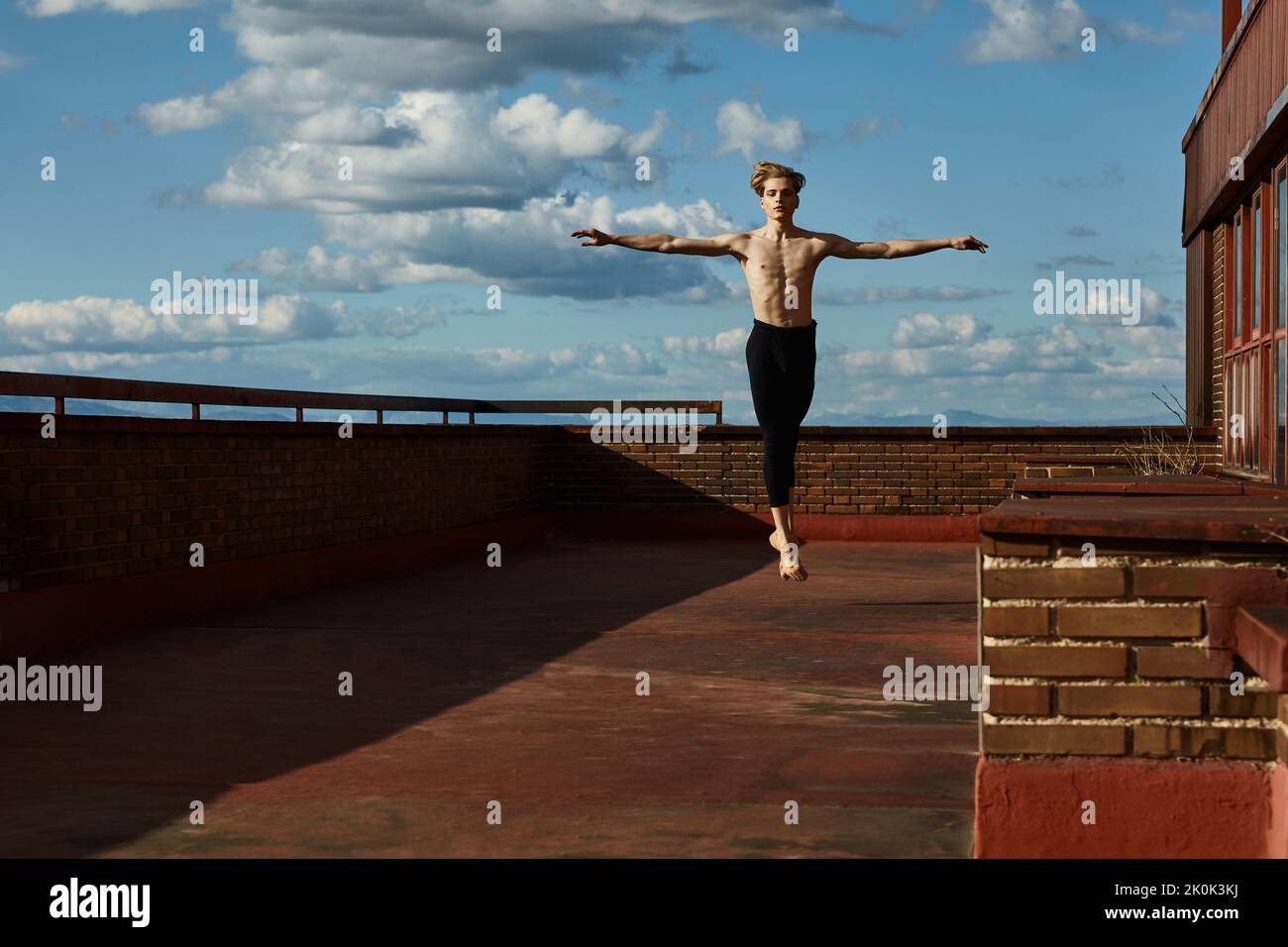 Masterful young blond ballet dancer in black leotard performing ...