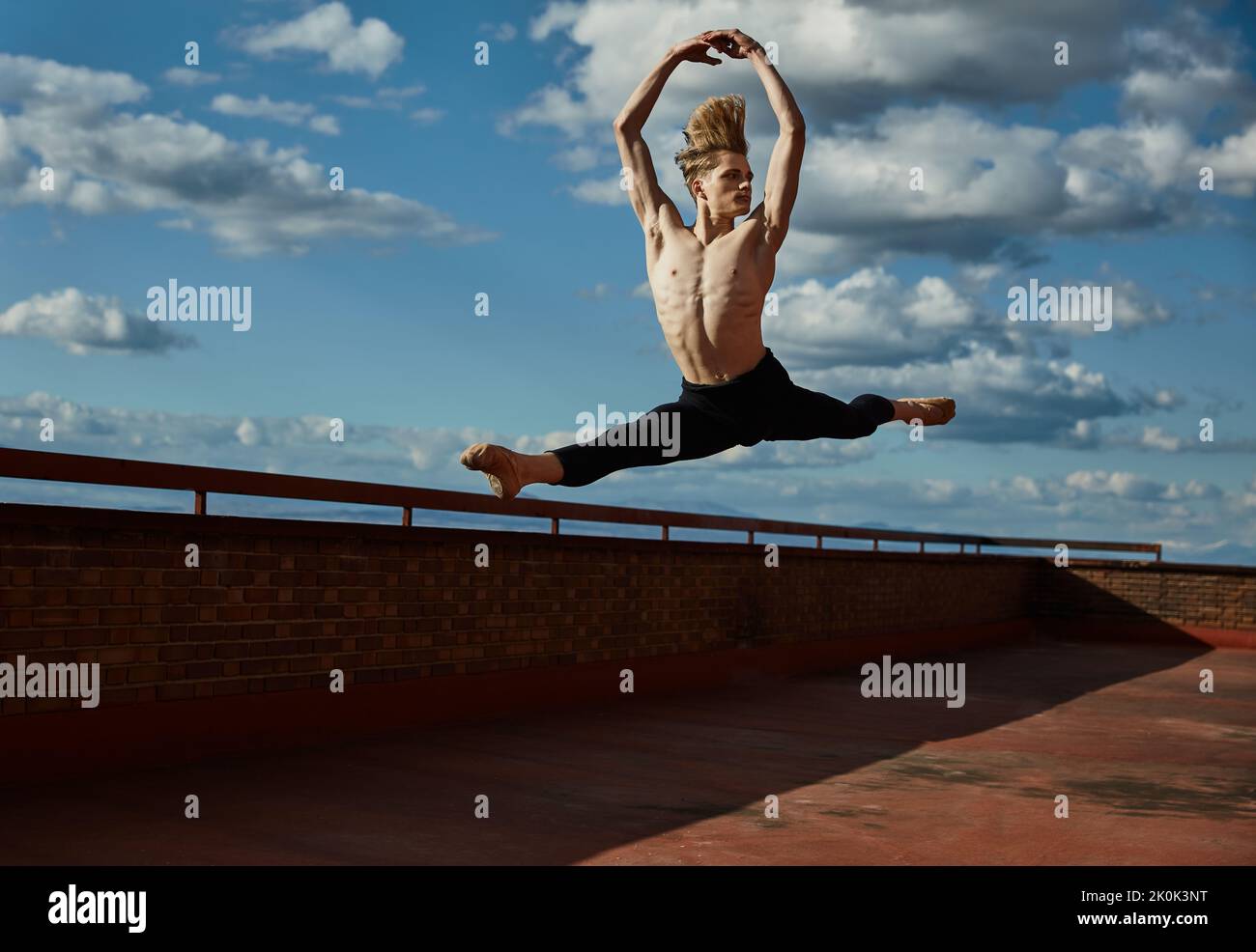 Masterful young blond ballet dancer in black leotard performing ...