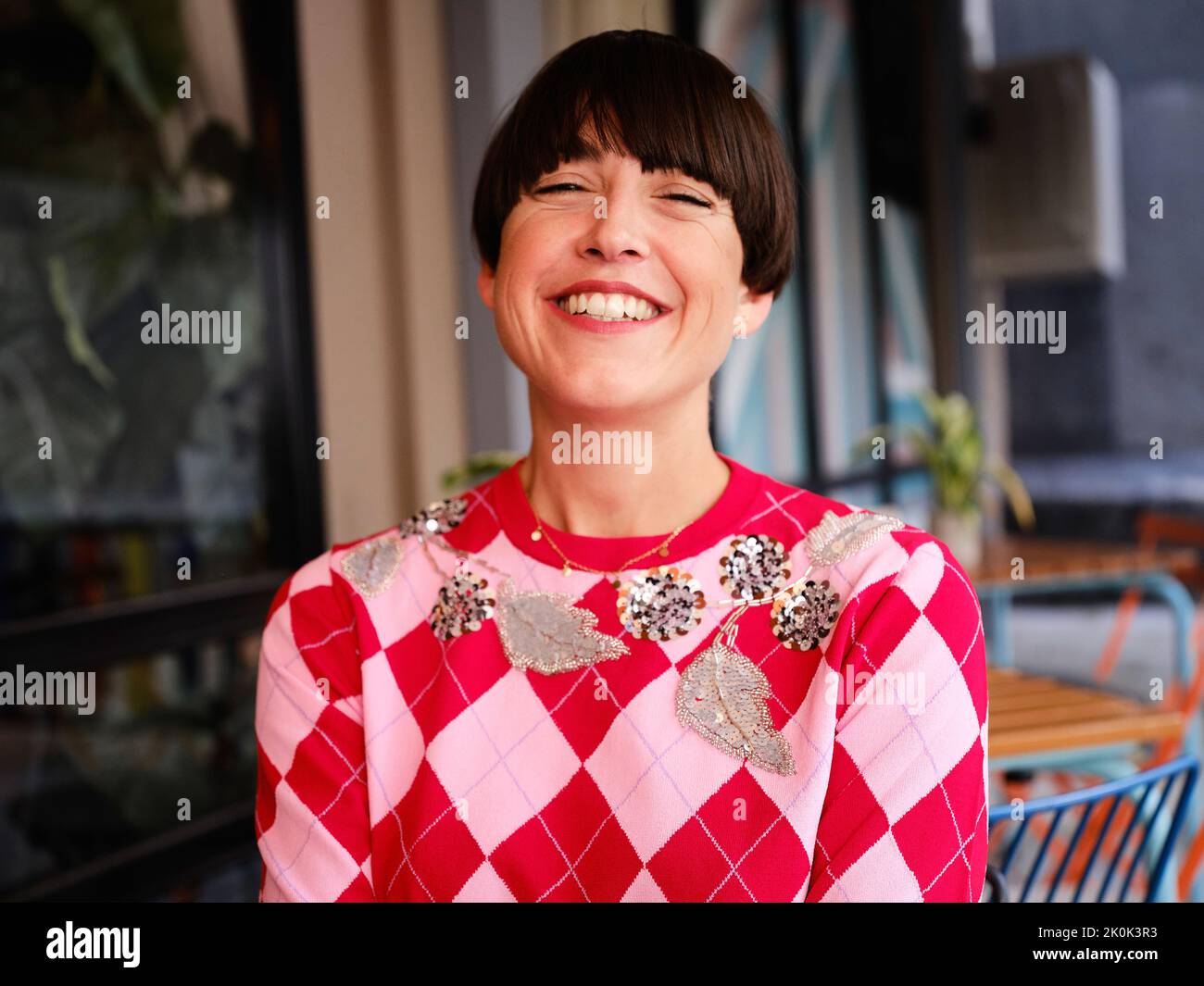 Cheerful Female In Trendy Outfit And With Bob Hairstyle Sitting In
