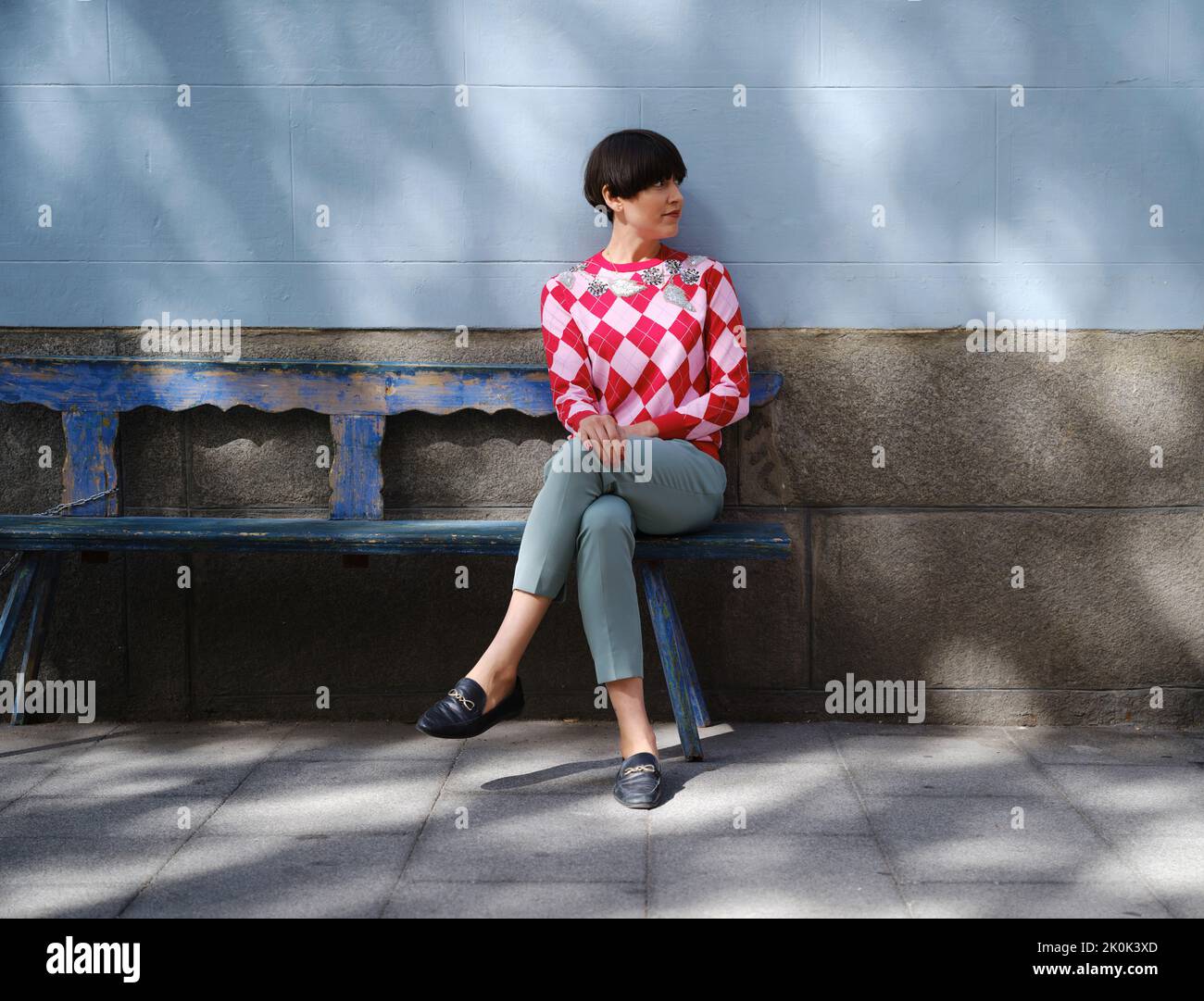 Calm female with stylish bob hairstyle sitting with crossed legs on ...