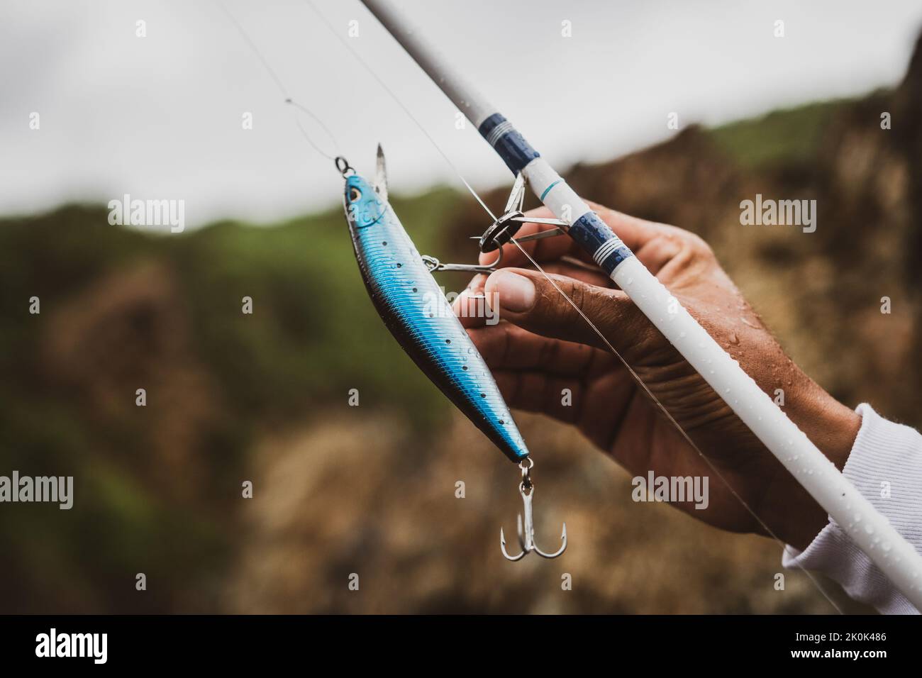 Crop anonymous male with special blue plug on fishing rod with hook ...