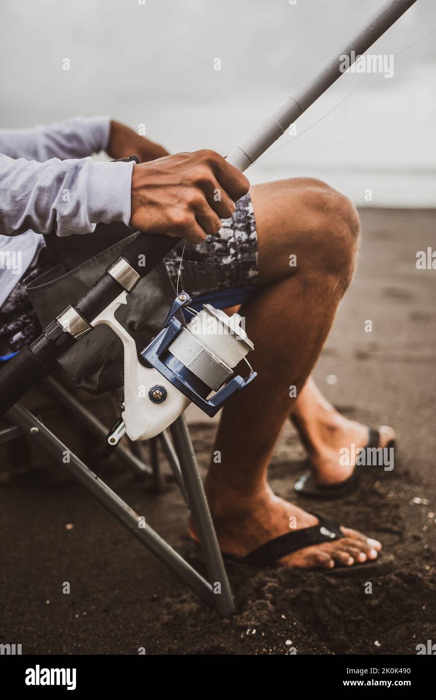 Side view of unrecognizable male with fishing rod catching fish on ...