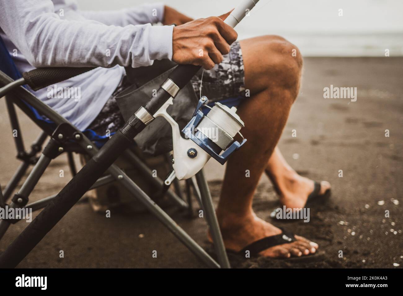 Side view of unrecognizable male with fishing rod catching fish on ...