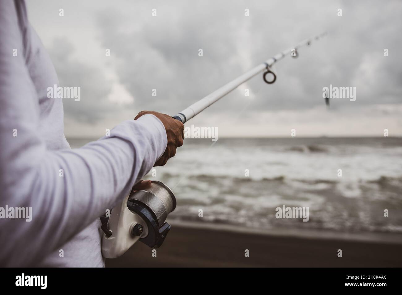 Crop side view of unrecognizable male with fishing rod catching fish on ...