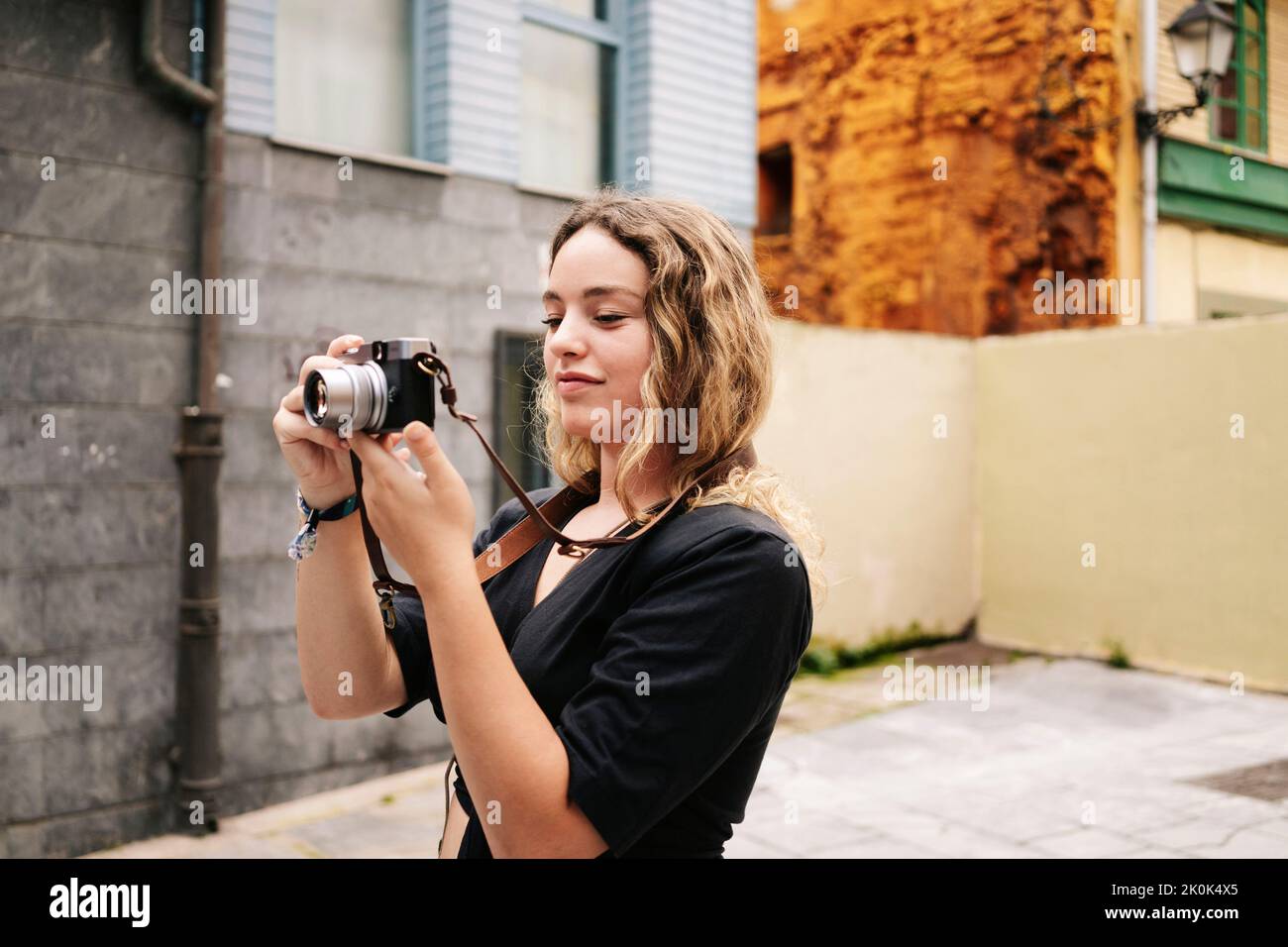 Charming friends hugging posing against wall while woman taking picture ...