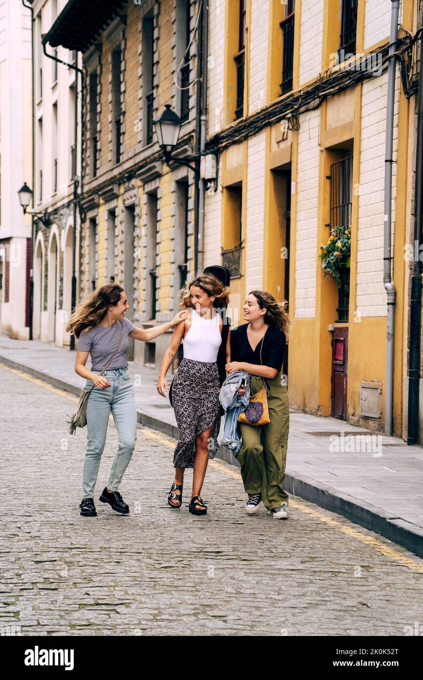 Meeting of young curly stylish women bonding and talking in city street ...