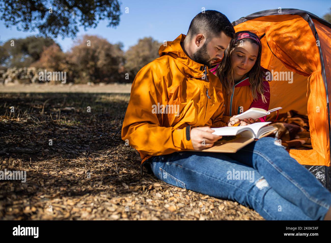 Focused young couple sitting in tent writing notes on notebook while ...