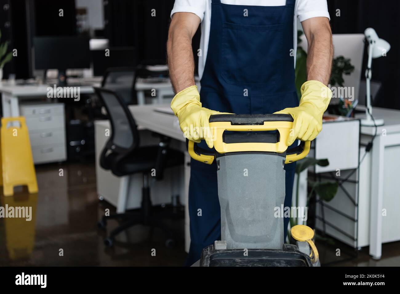 cropped view of man with floor scrubber machine working in blurred ...