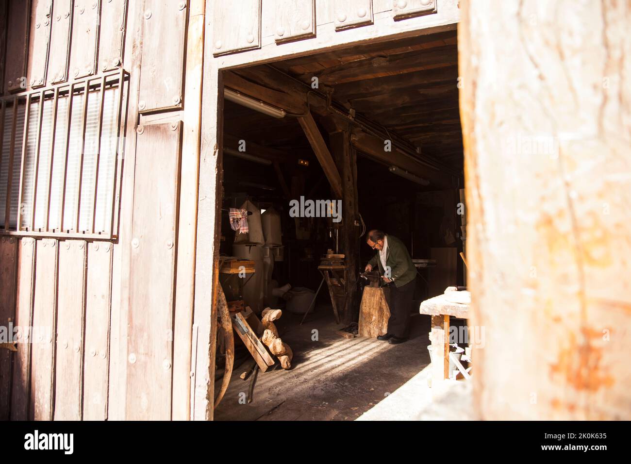 Side view of senior craftsman standing inside old barn and working with ...