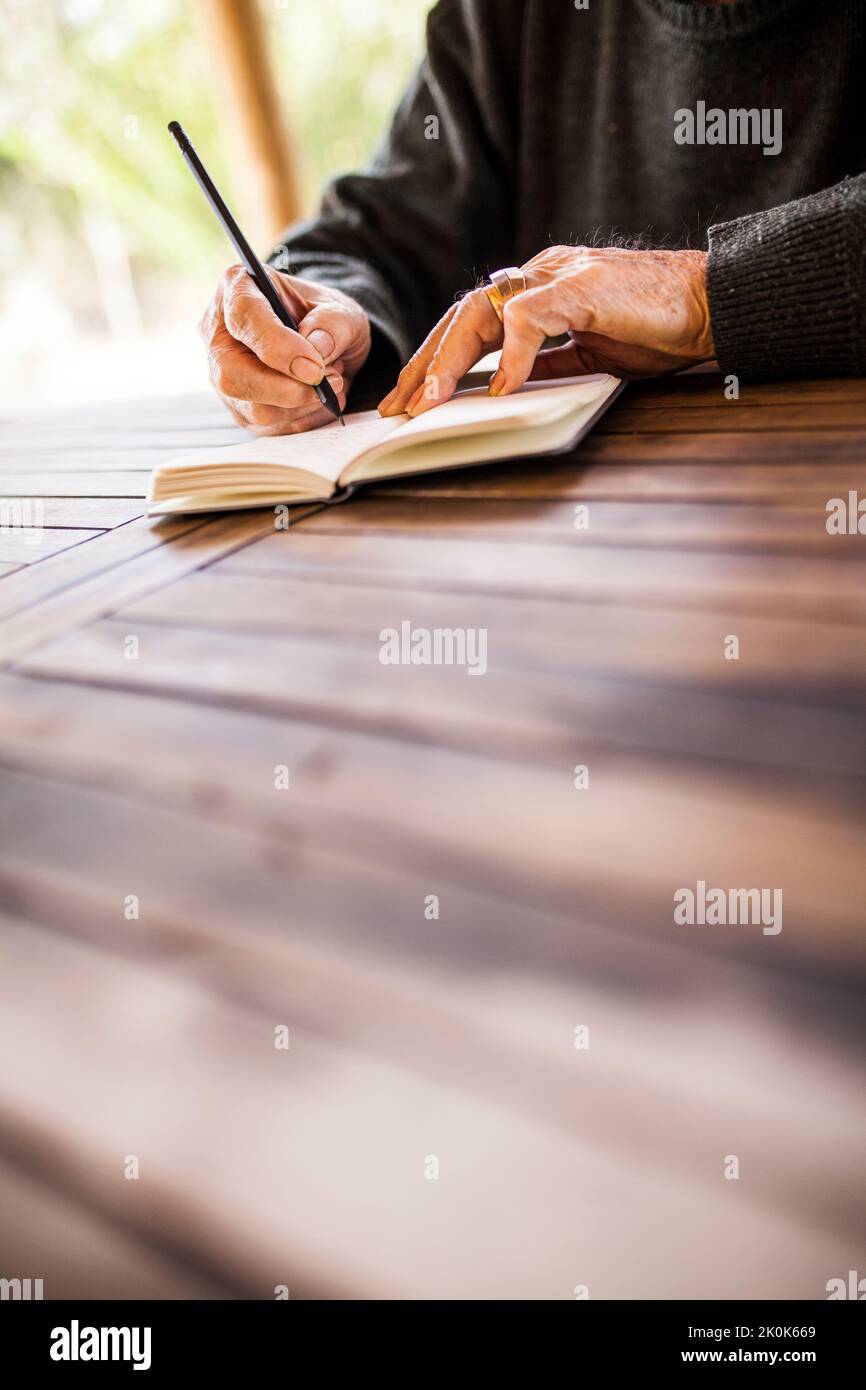 Elderly man writing in his notebook on the porch of his house Stock ...