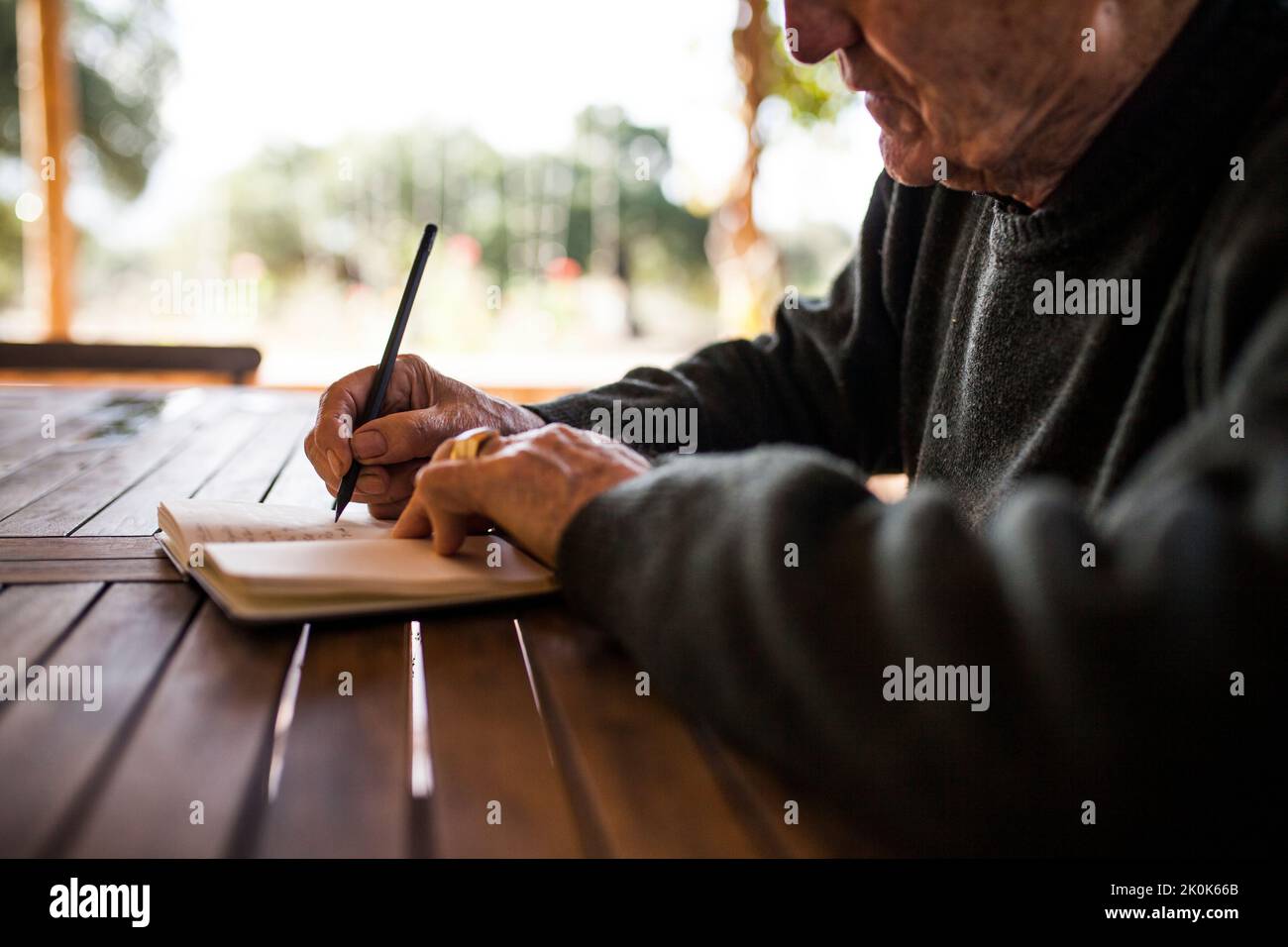 Elderly man writing in his notebook on the porch of his house Stock ...