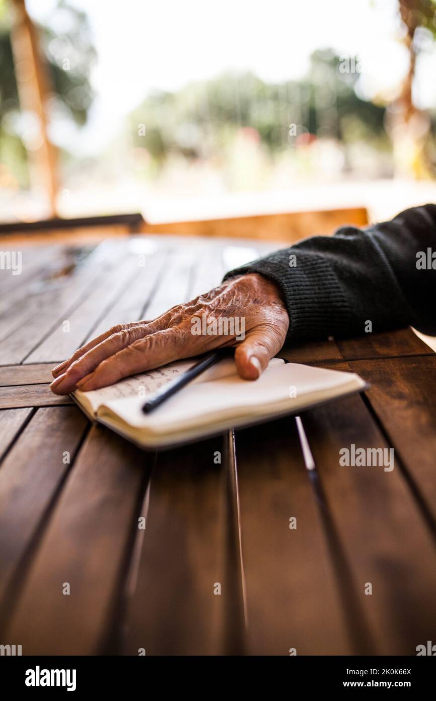 Elderly man writing in his notebook on the porch of his house Stock ...