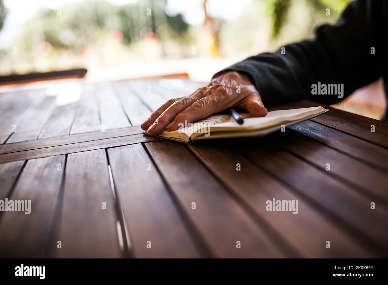 Elderly man writing in his notebook on the porch of his house Stock ...