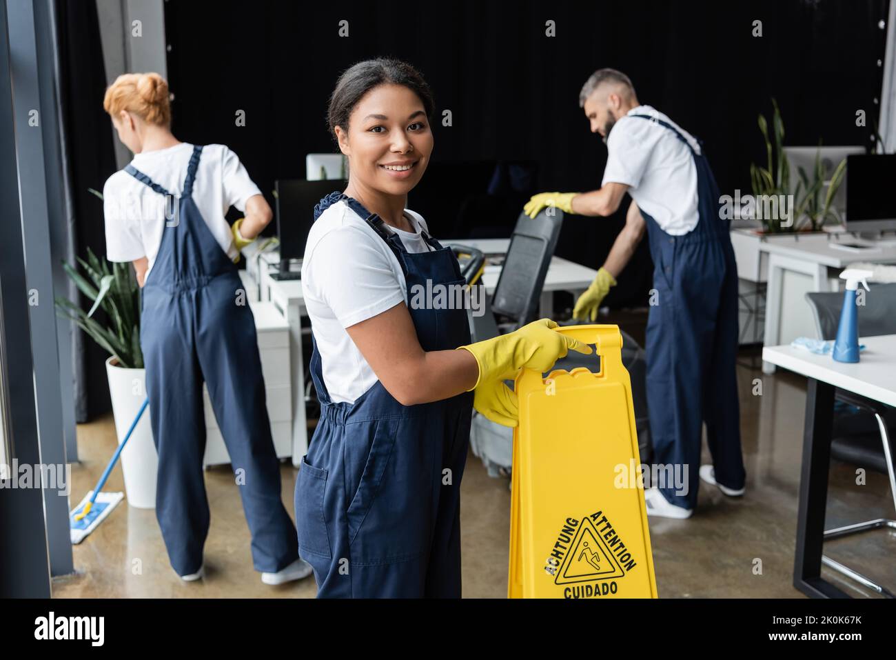 happy bi-racial woman with warning sign board looking at camera near ...