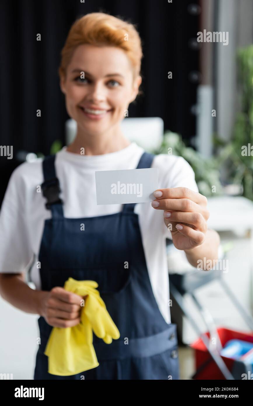blurred professional cleaner showing empty business card while smiling ...