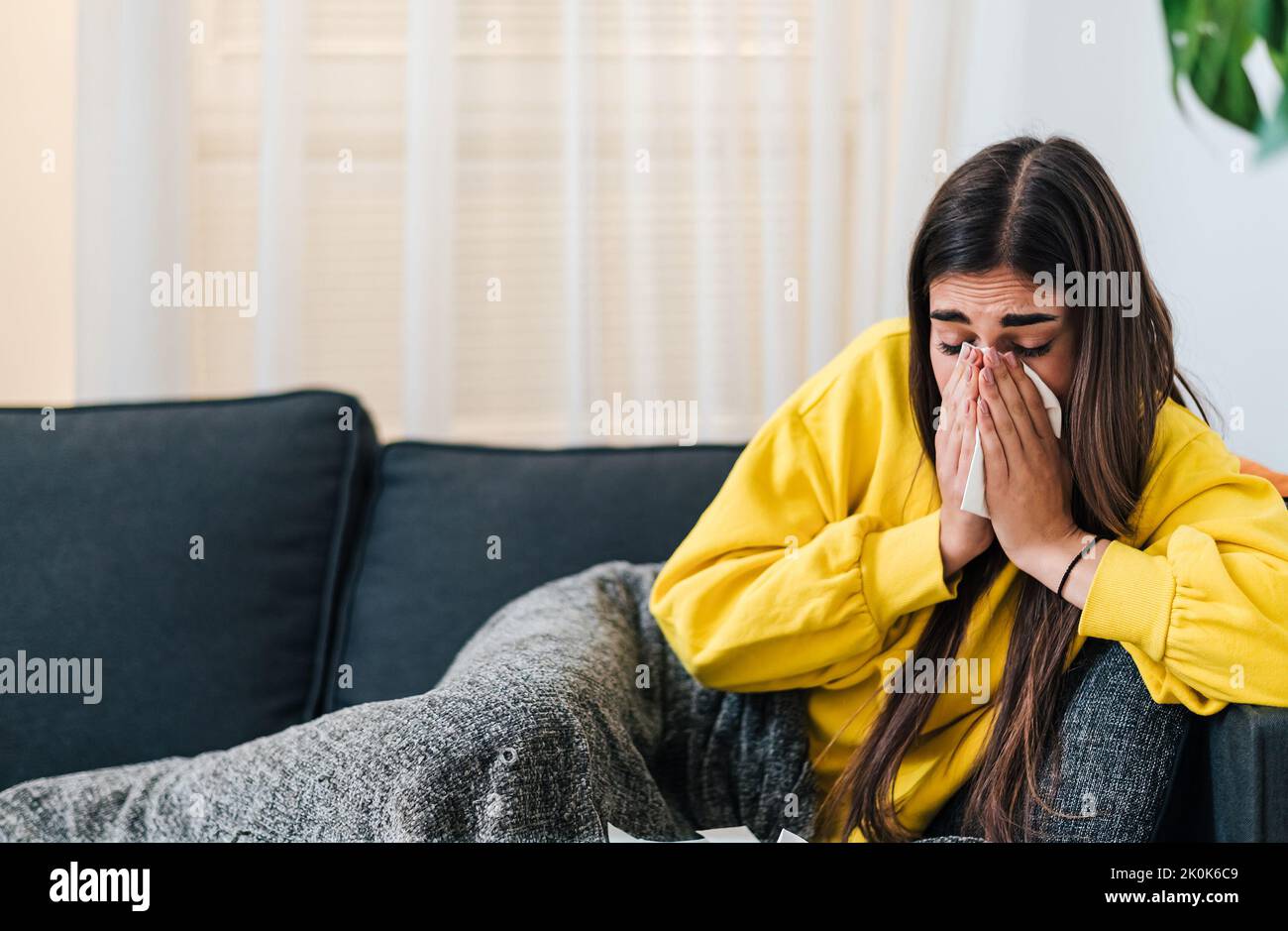 Fatigued young brunette woman, laying sick at home on the couch ...