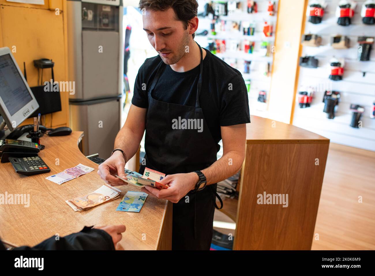 Salesman counting cash over counter for crop customer in modern store ...