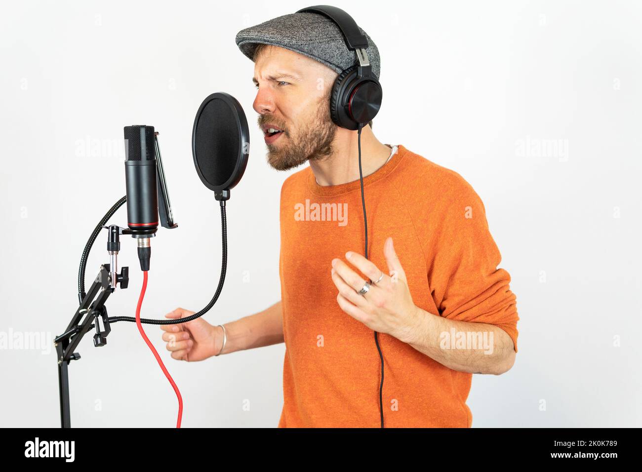 Skilled male singer in casual wear with headphones recording song in ...