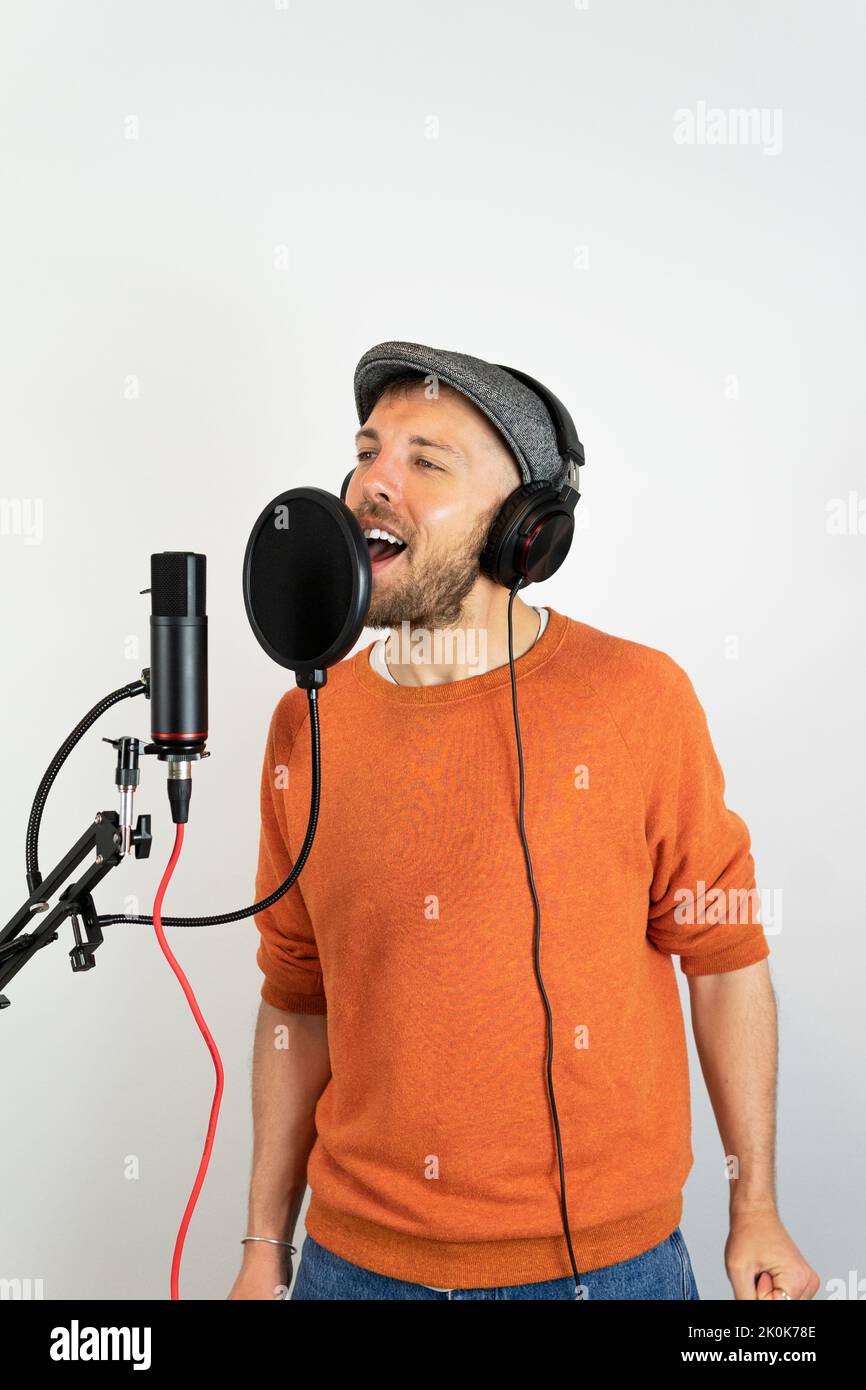 Skilled male singer in casual wear with headphones recording song in ...