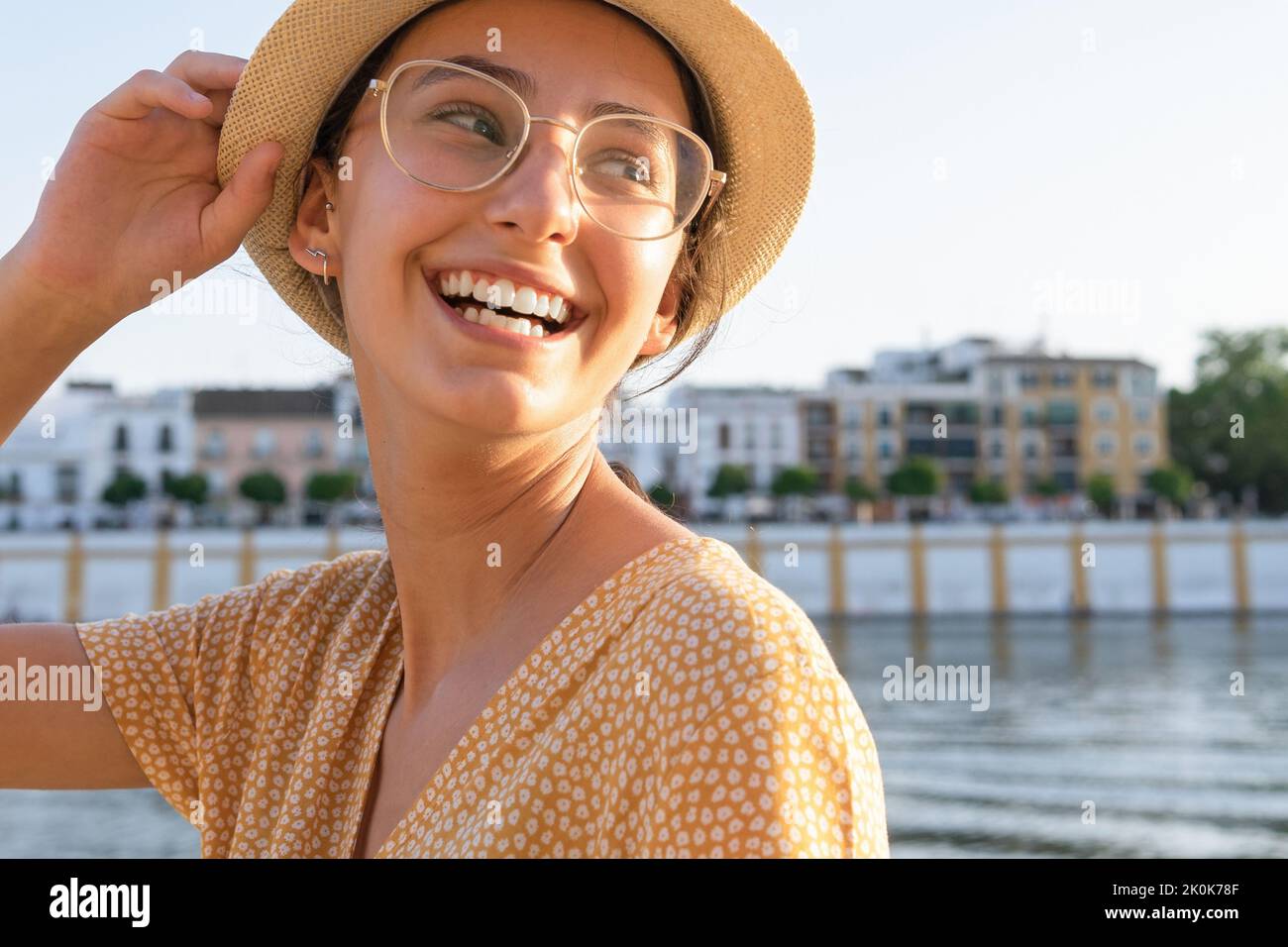 Side view of delighted female sitting on embankment near river in city ...