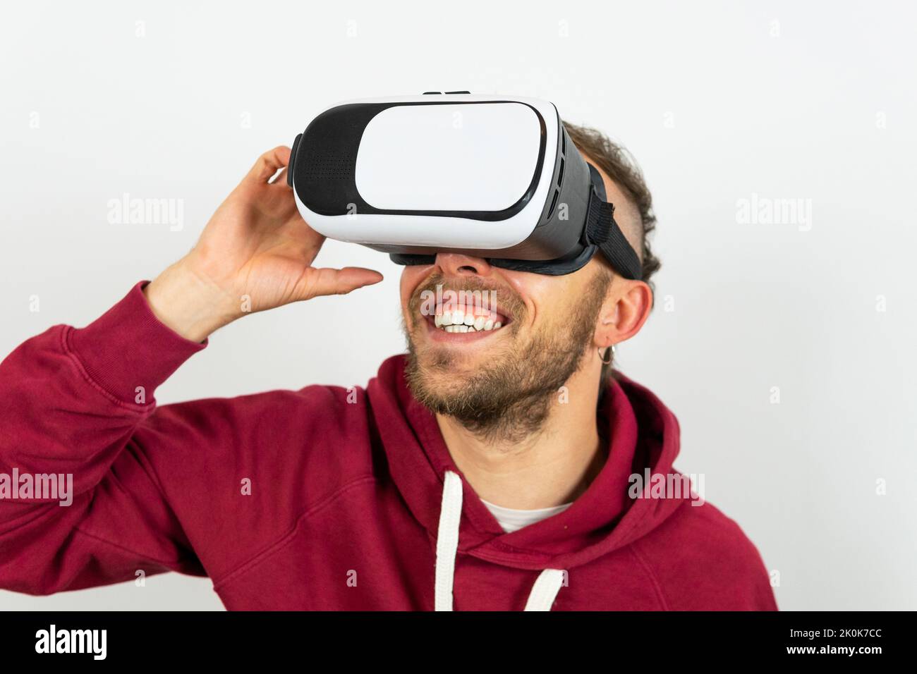 Joyful male in modern VR goggles smiling while exploring virtual ...