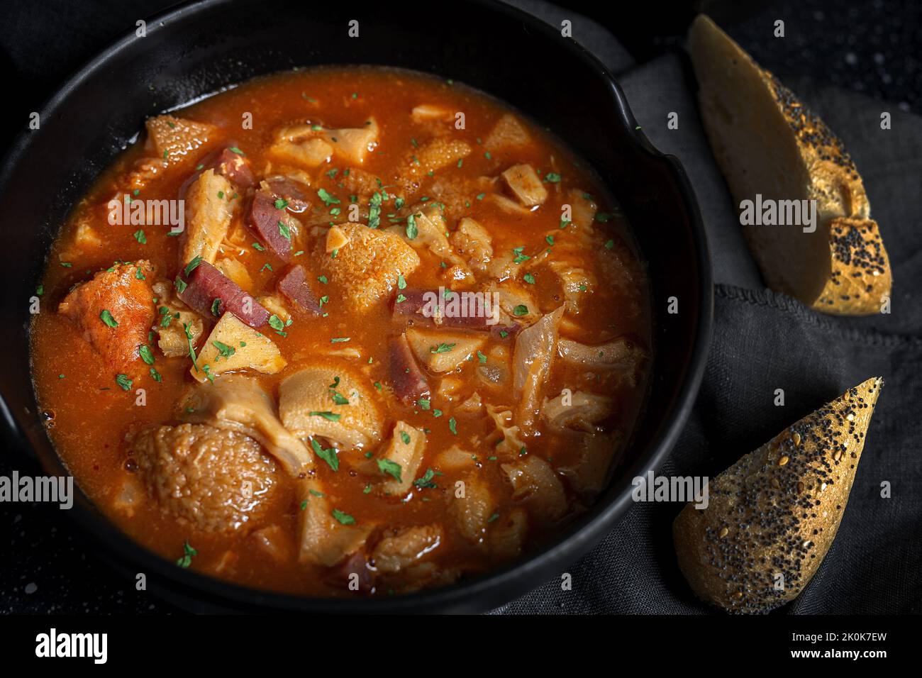 From above of tasty callos a la madrilena in black bowl near bread with ...