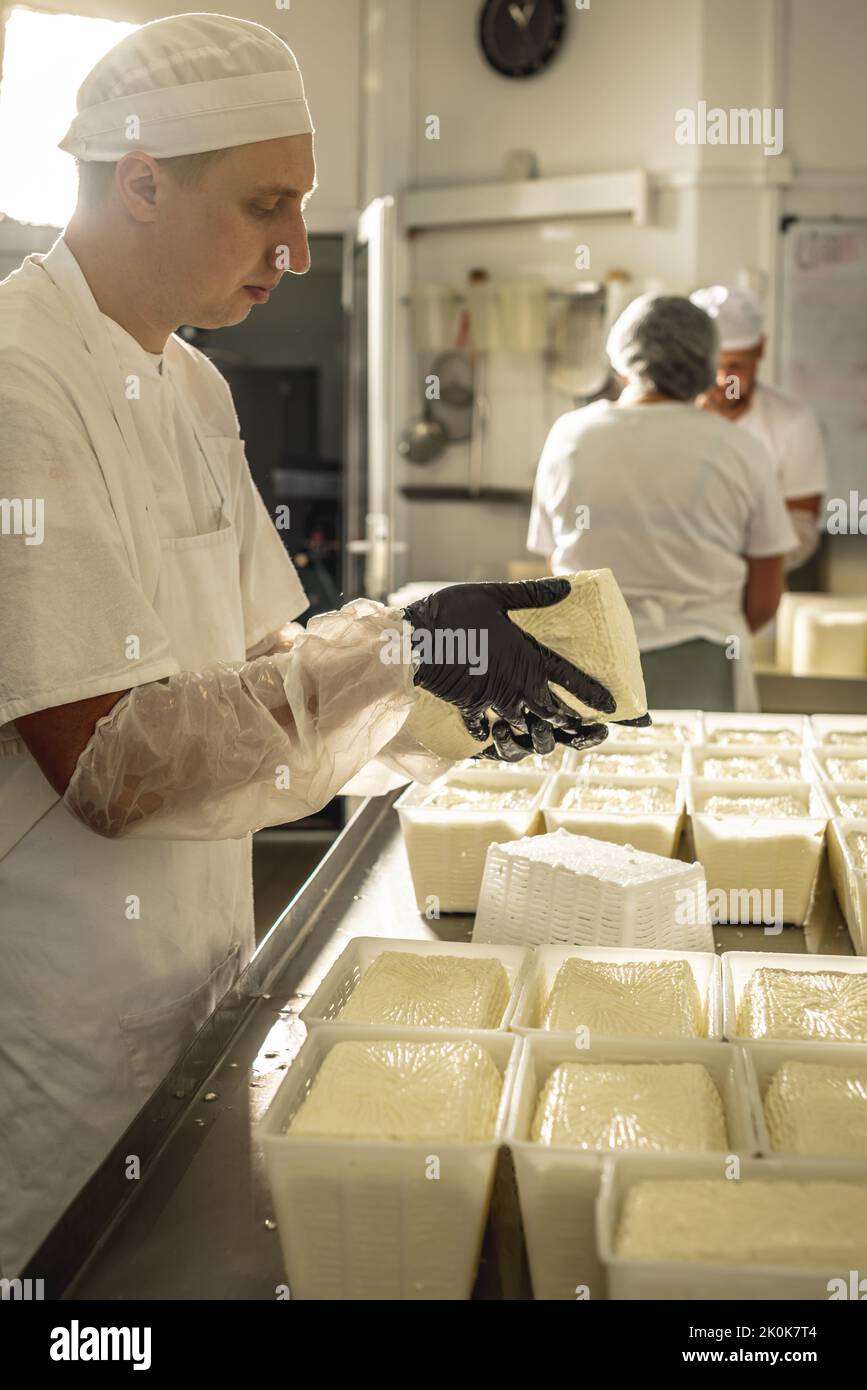 A man is a cheese maker in the process of producing different varieties ...