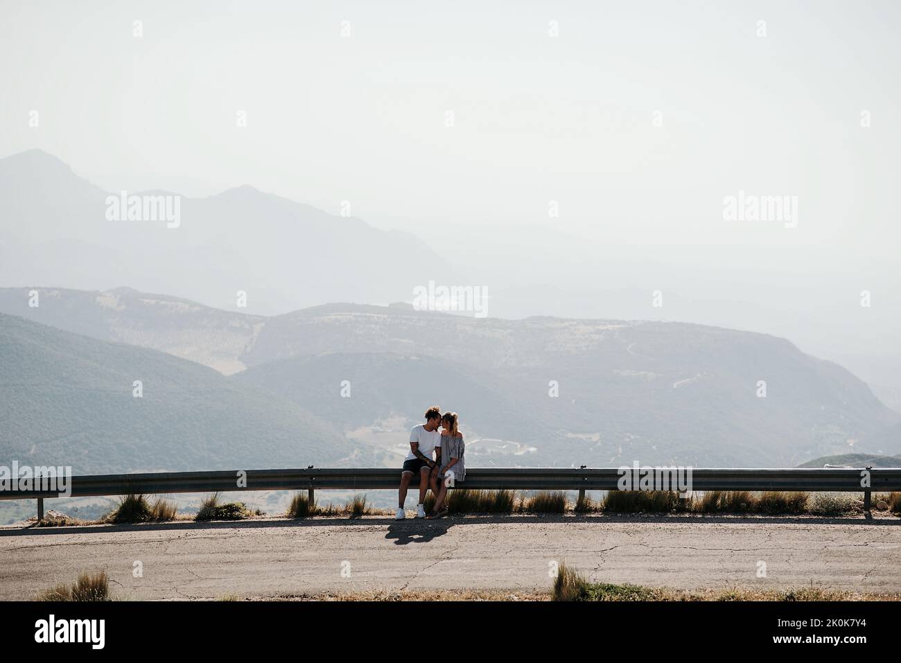 From below young man embracing and kissing girlfriend while sitting on ...