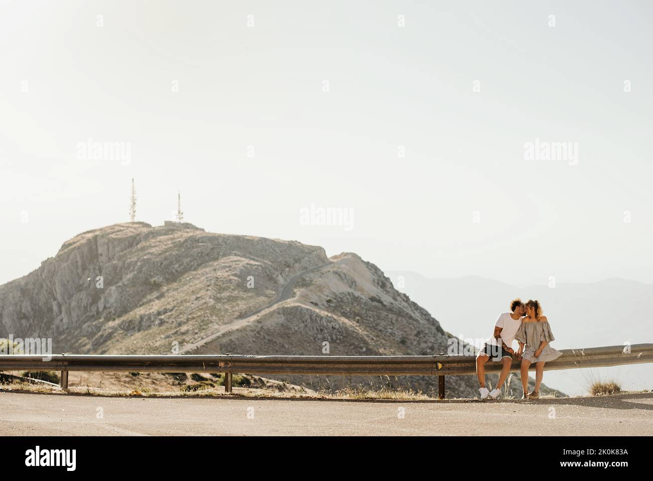 From below young man embracing and kissing girlfriend while sitting on ...