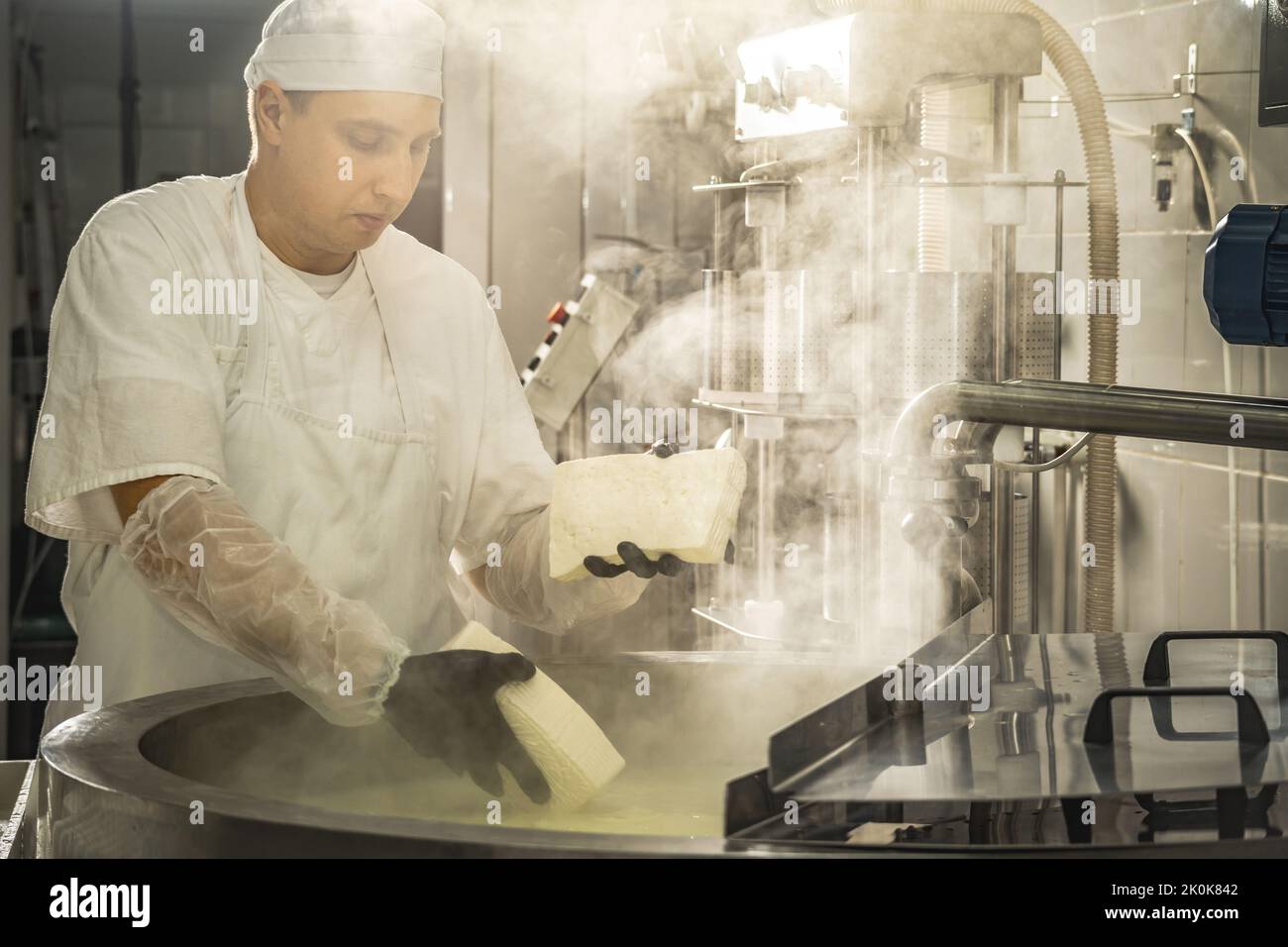 A man is a cheese maker in the process of producing different varieties ...