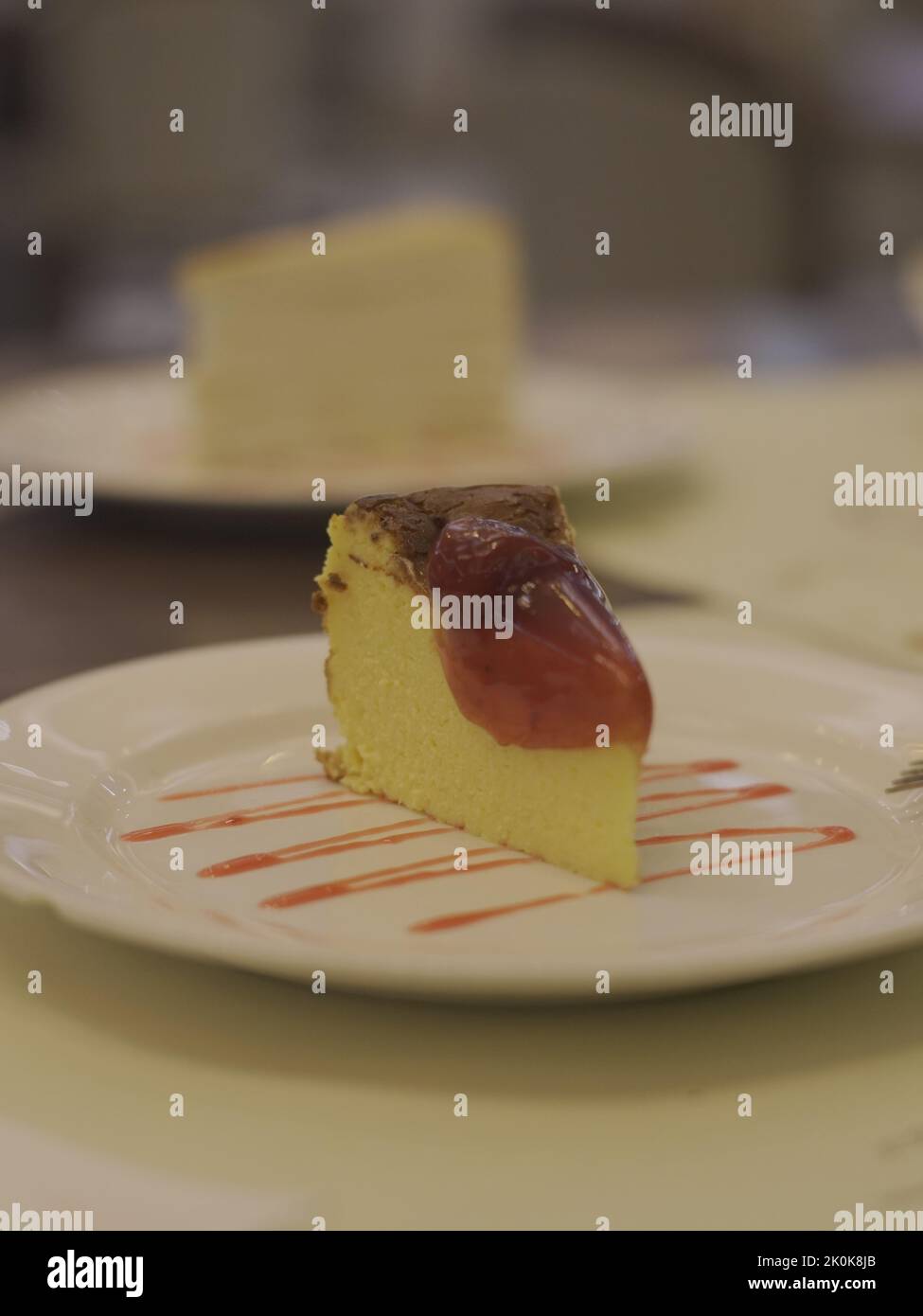 a vertical shot of a cherry cheesecake on a white plate with a blurred background Stock Photo ...