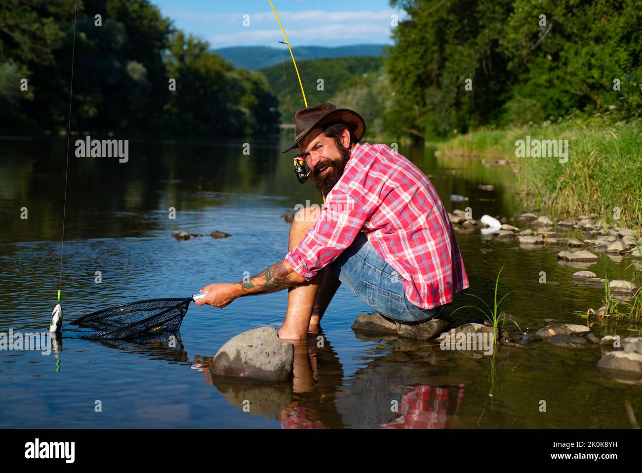 Fisherman fishing on a rever. Relaxed fisher man with a fishing rod on ...