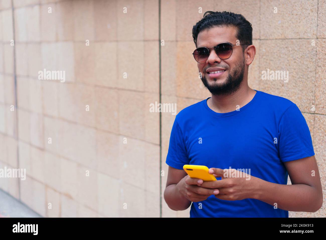 Glad ethnic male standing in street and browsing social media on ...