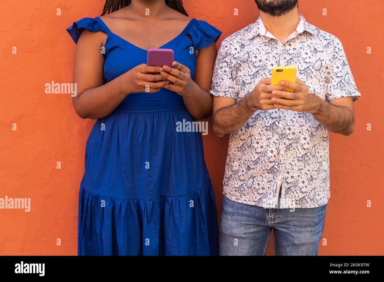 Anonymous multiracial couple standing messaging on mobile phones on ...