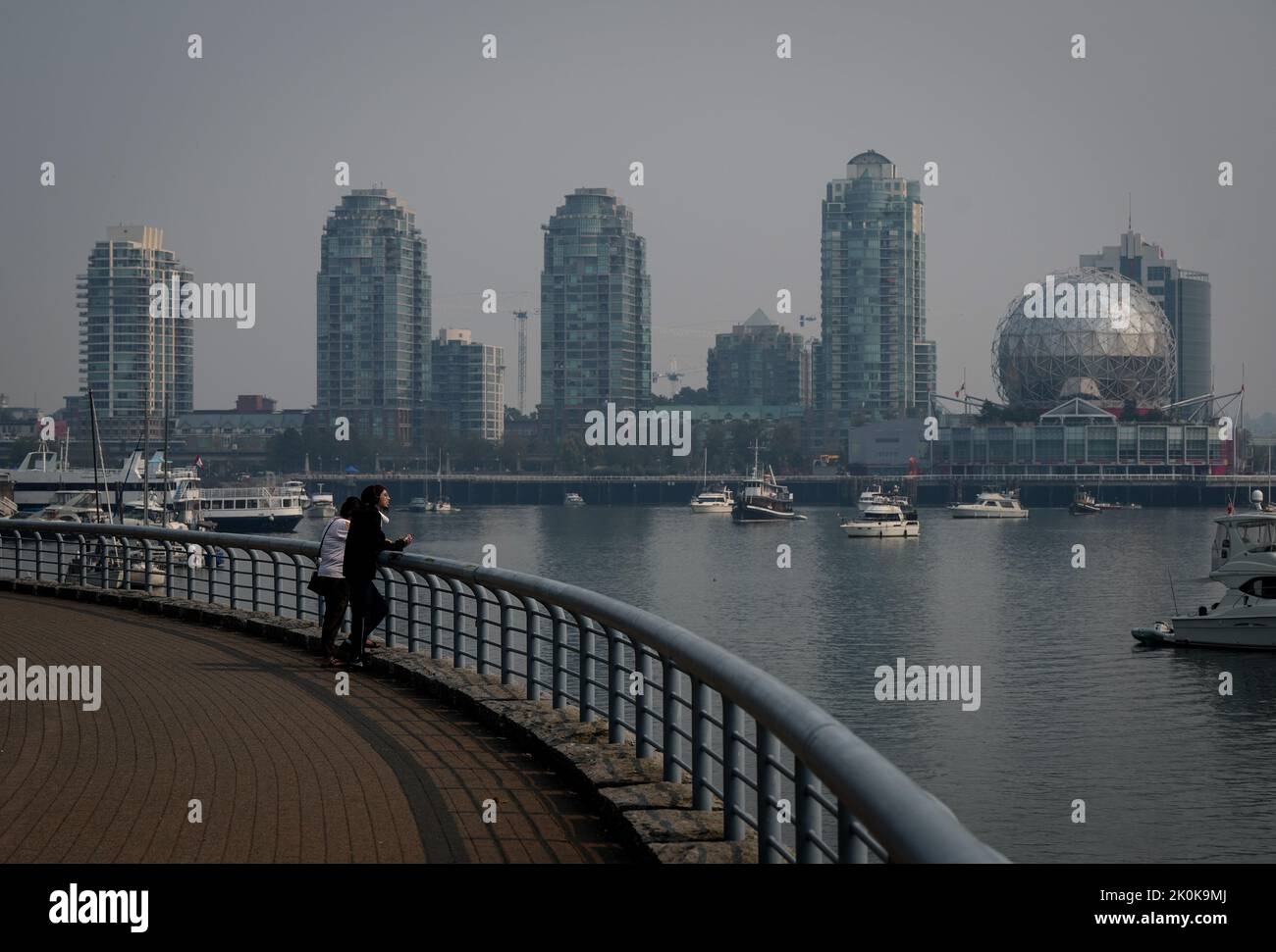 Smoke obscures condo towers and Science World as people stands on the ...