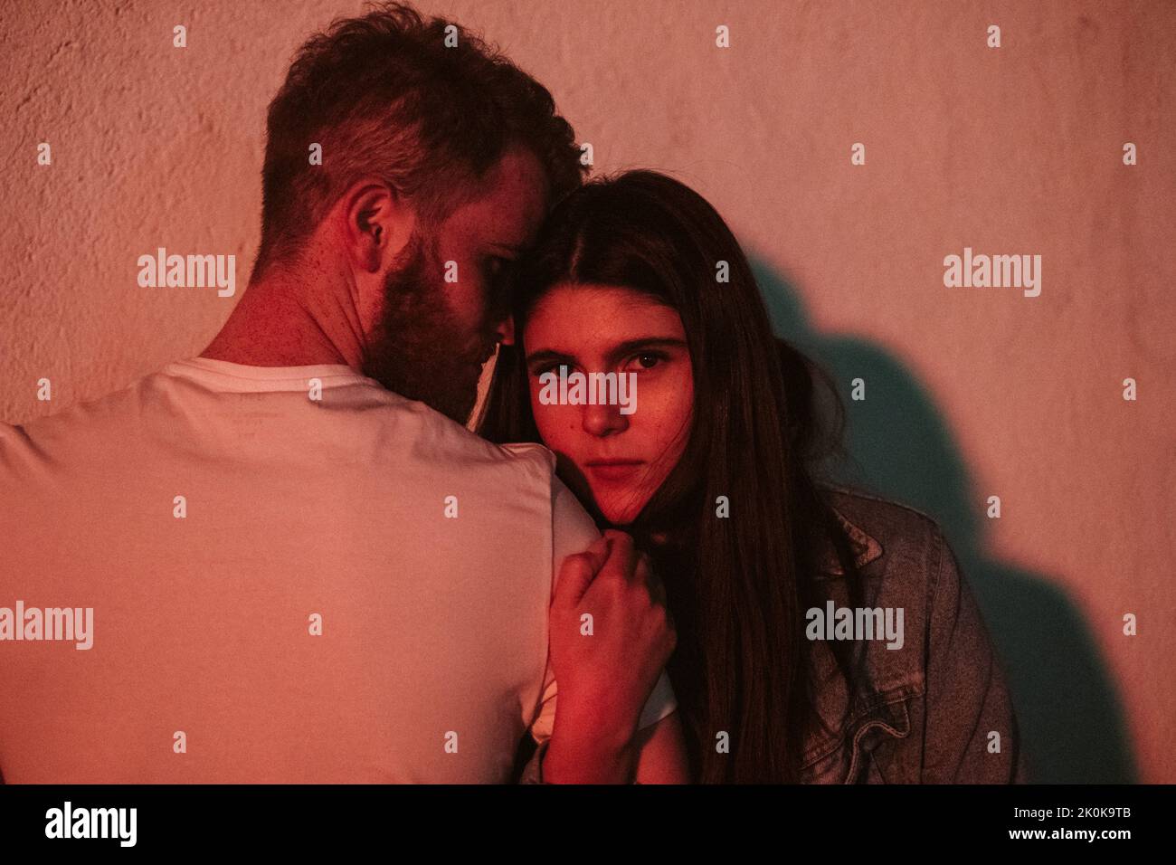 Young couple standing close to each other hugging outdoors against a ...