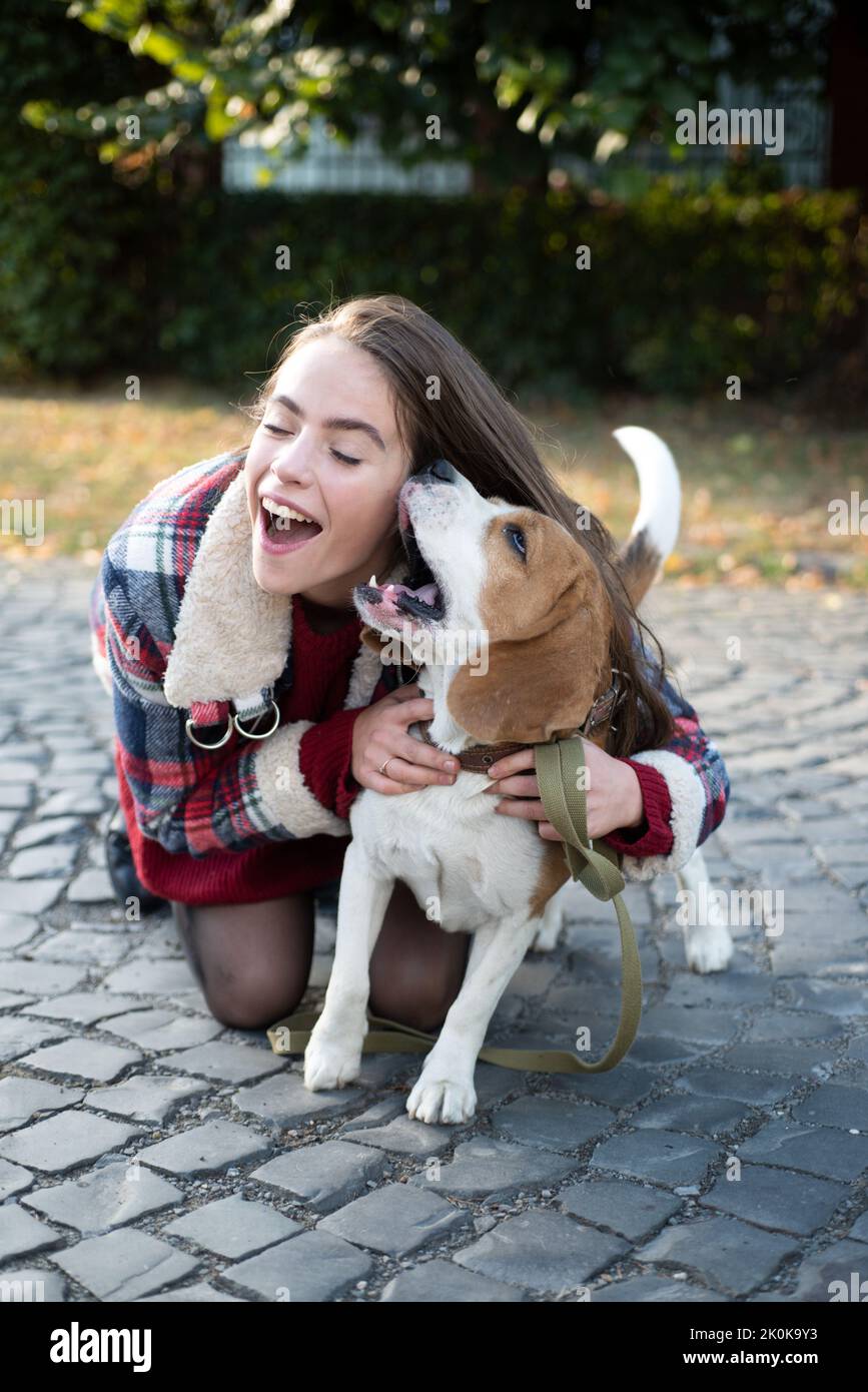 Woman embracing puppy dog outdoor. Happy girl gets lovely dog, plays ...