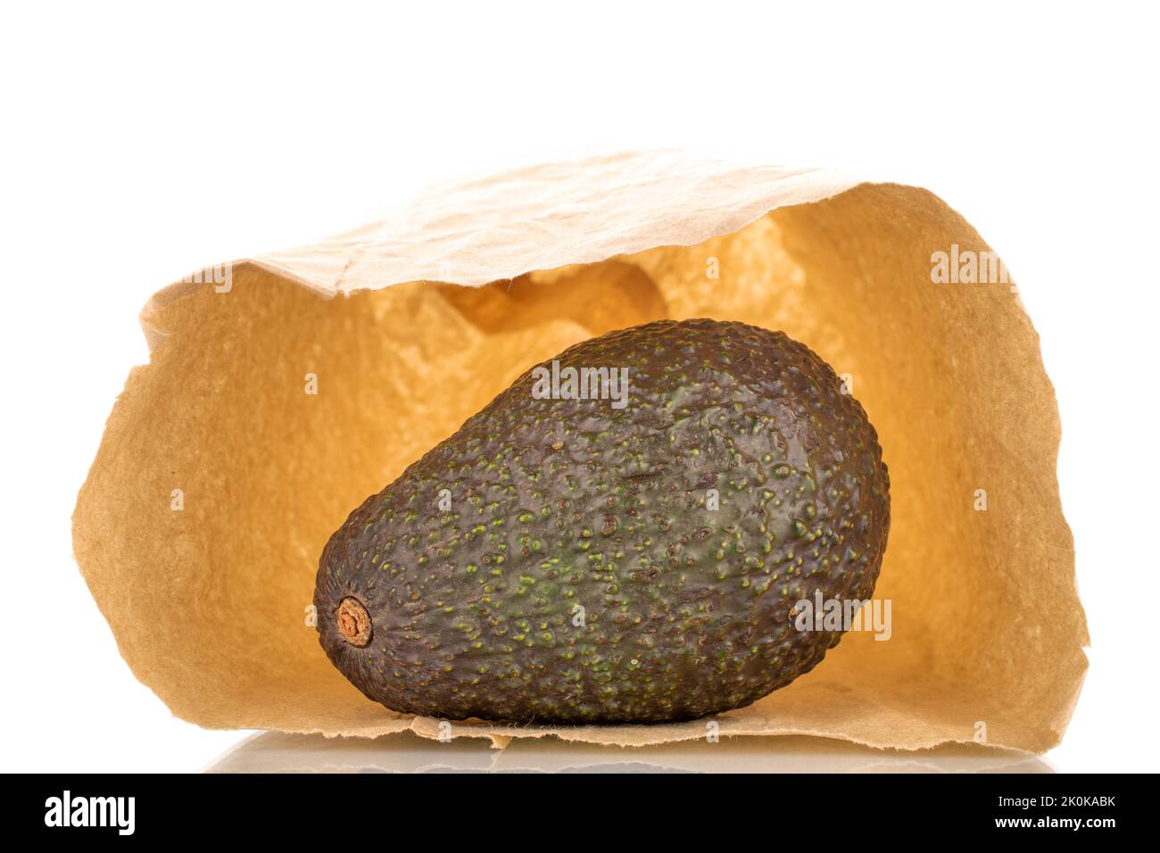 One ripe organic avocado in a paper bag, close-up, isolated on a white ...