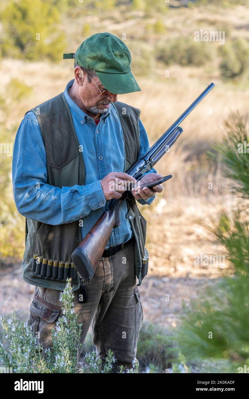 Male hunter in special hunting vest and green cap holding rifle and ...