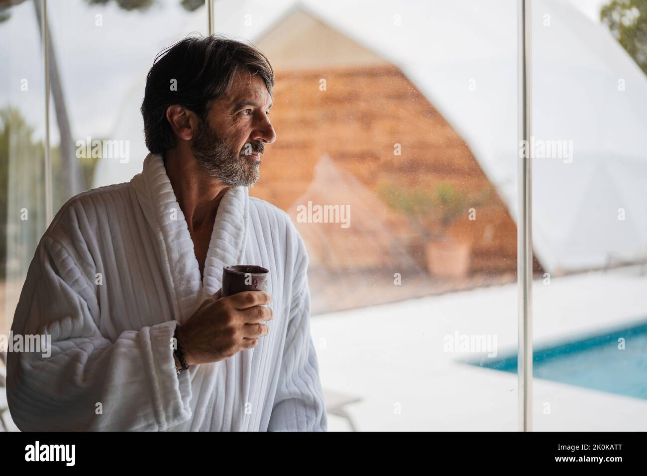 Contemplated senior gray haired male dressed in white soft bathrobe ...