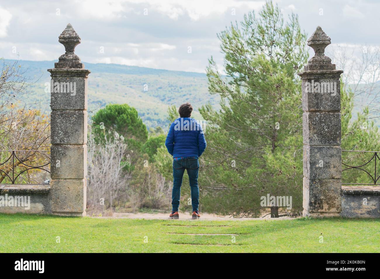 Back view of middle-aged man standing between a stone columns while ...