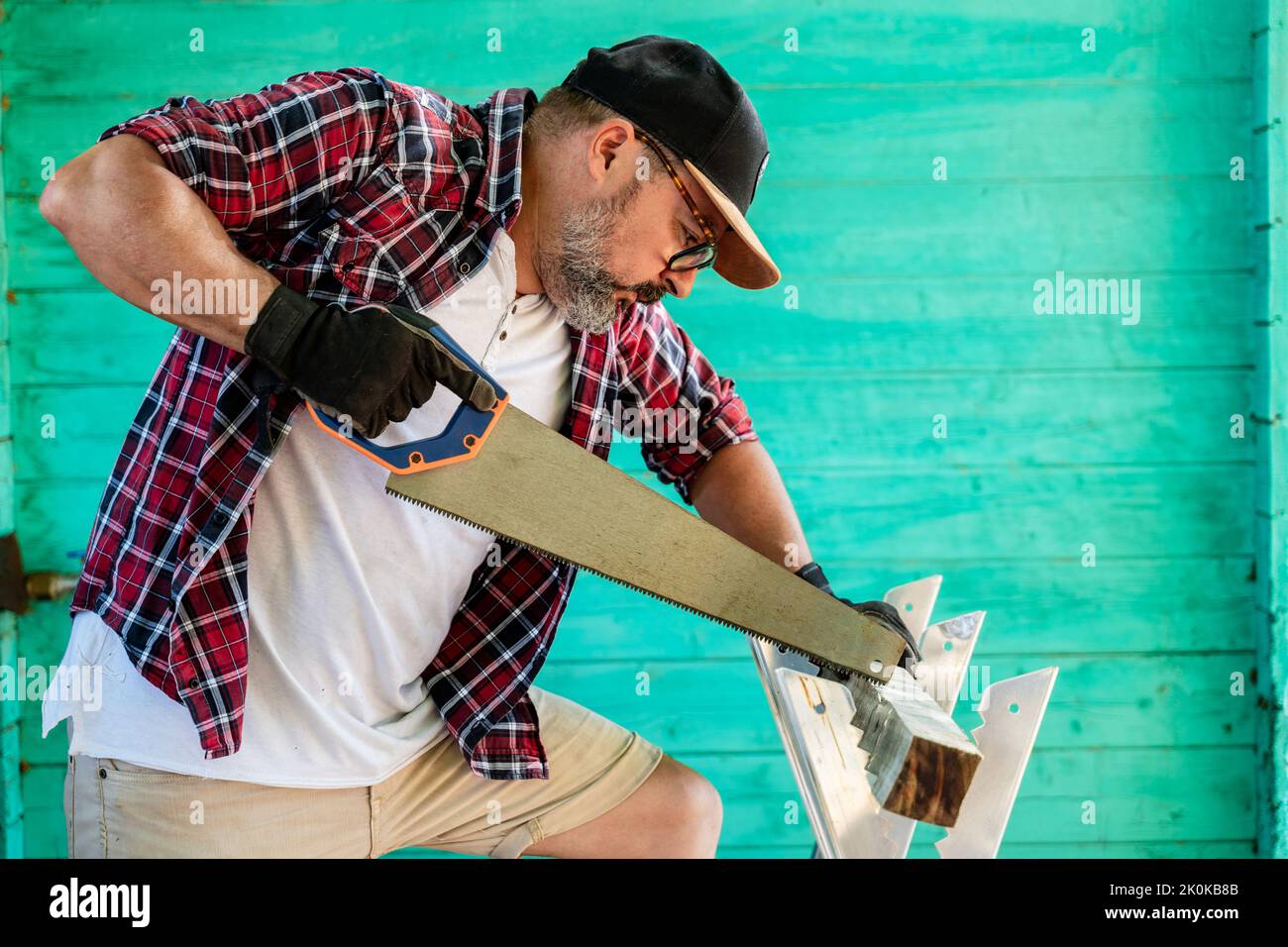 Side view of mature carpenter in own workshop standing at workbench and ...
