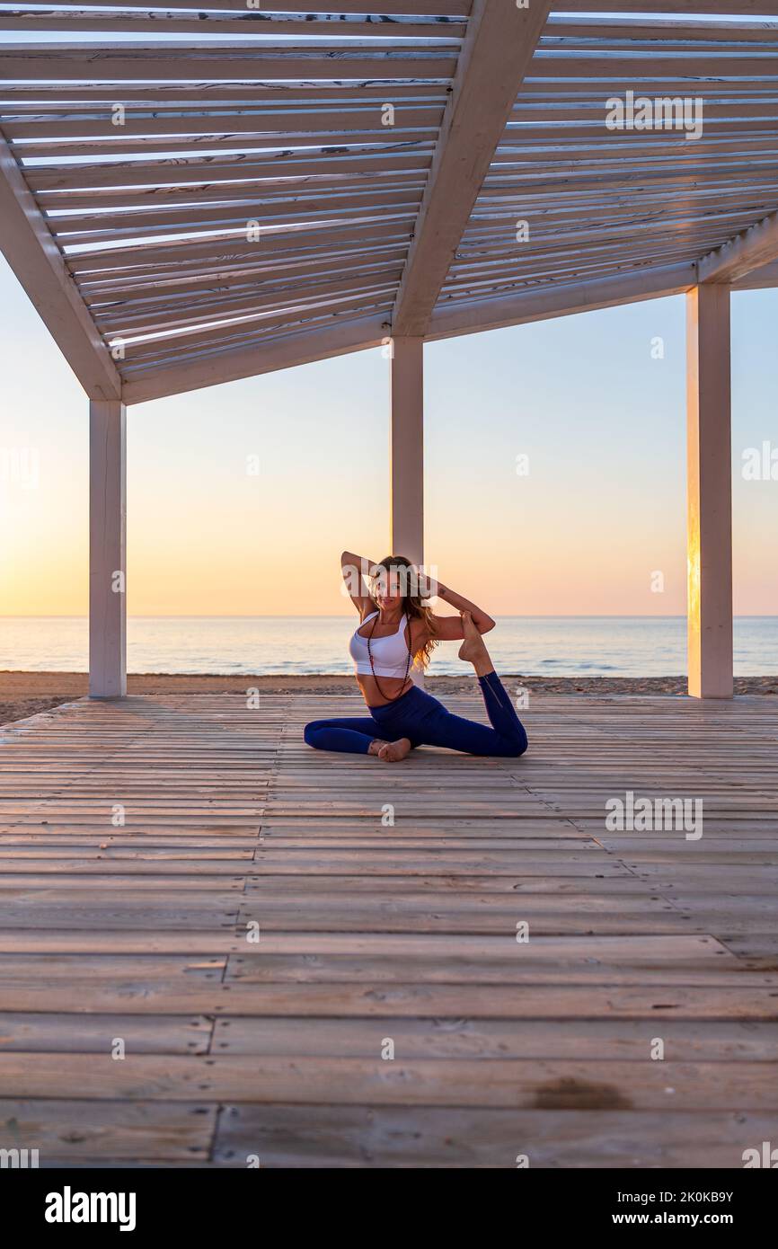 Side view of concentrated female practicing yoga in Mermaid asana while ...
