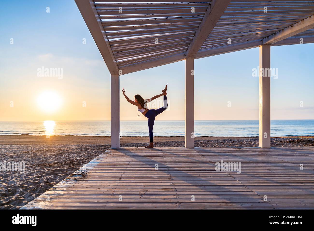 Side view of flexible female in sportswear balancing on leg and ...