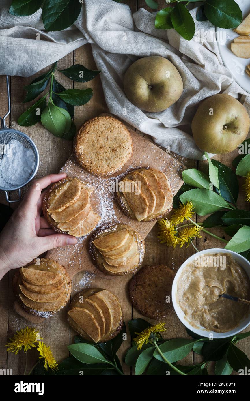 Anonymous person taking delicious apple tartlet from table in kitchen ...