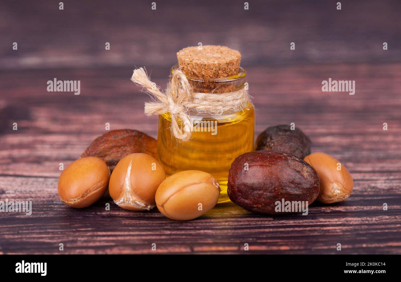 Argan oil on wooden background. Argan nuts and seeds, for cosmetic and ...