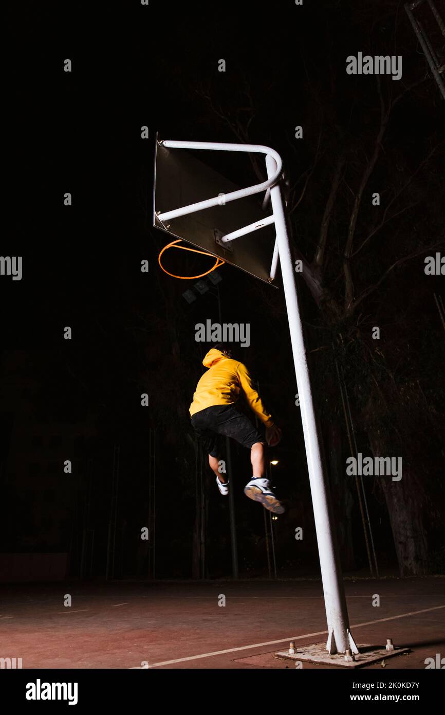 Basketball player in yellow sport clothes jumping and making dunk while ...