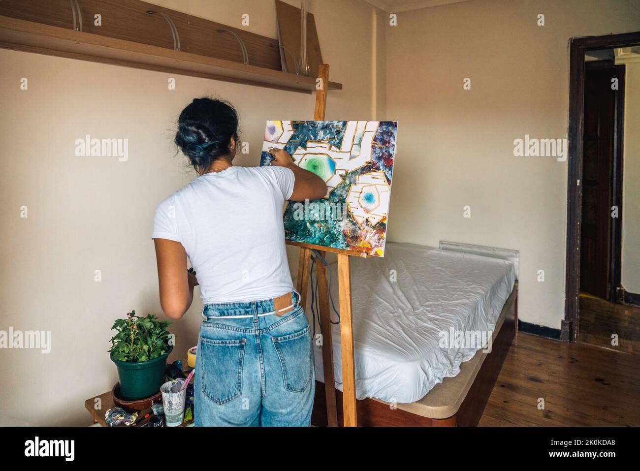 Back view anonymous female painter in white shirt drawing lines on ...