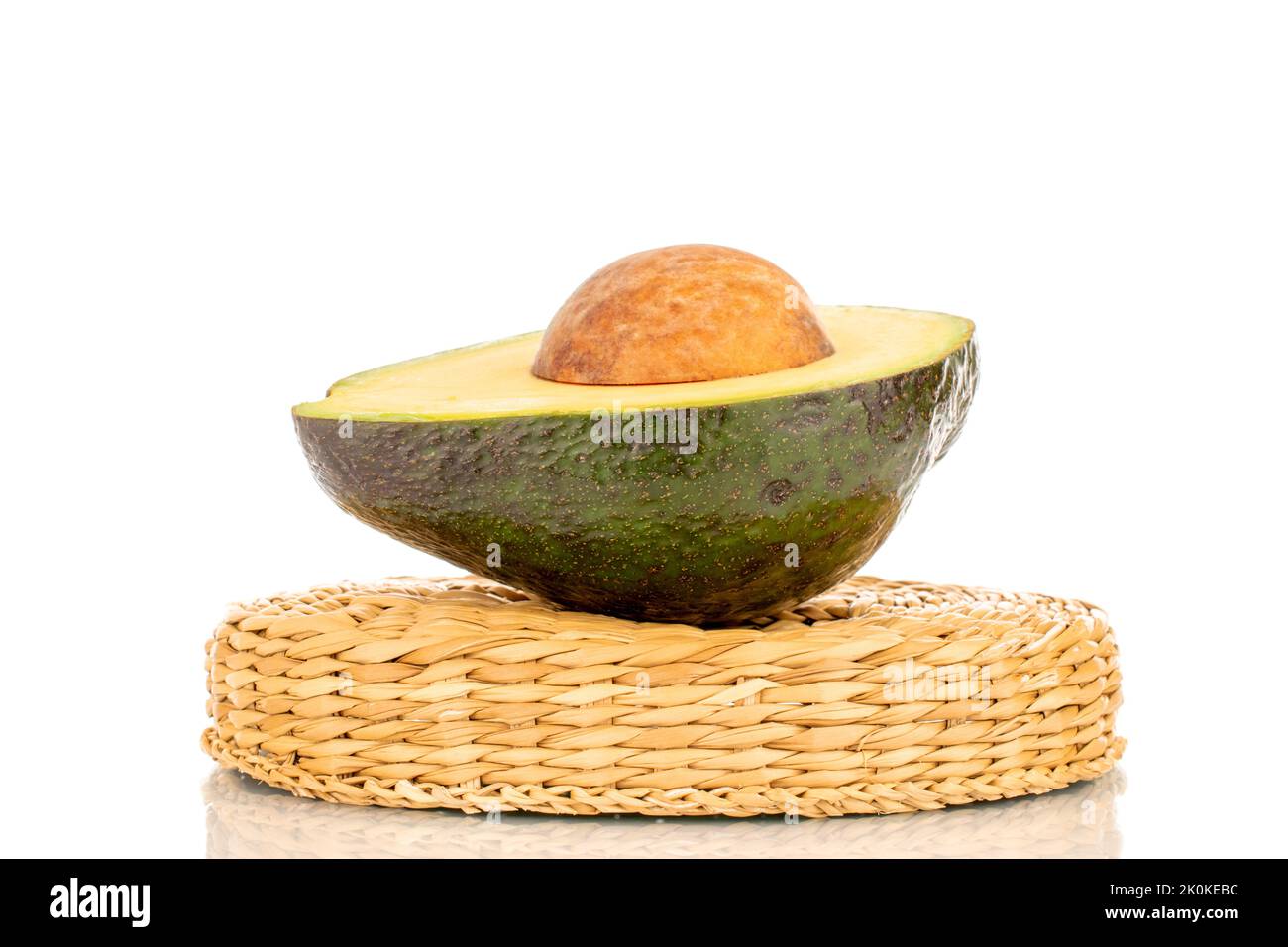 One half of a ripe organic avocado on a straw tray, close-up, isolated ...