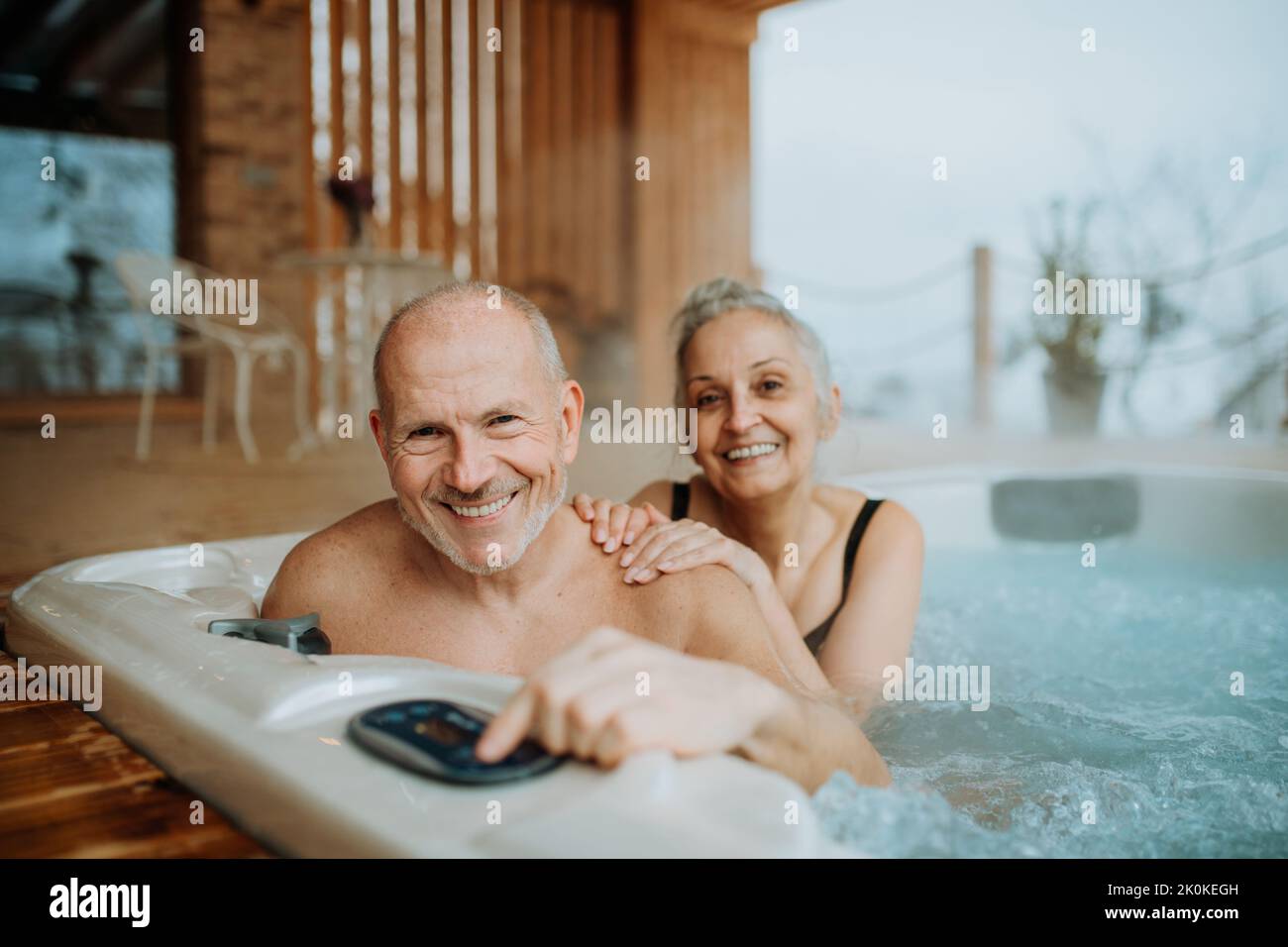Senior couple enjoying together outdoor bathtub at their terrace during ...